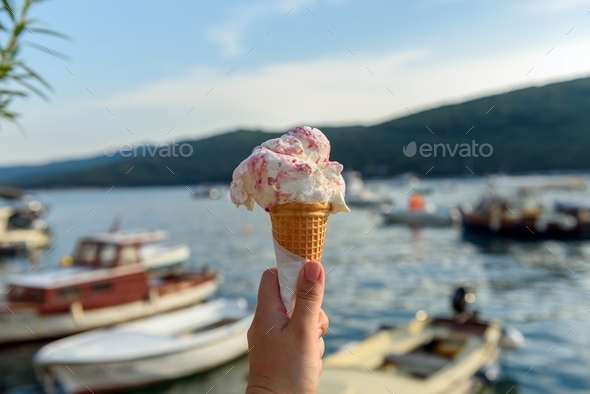 Personal perspective of hand holding two ice cream in cone on ...
