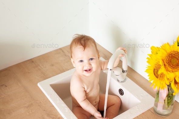 Baby taking bath in kitchen sink. Little boy bathing. Water fun for ...