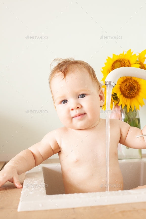 Baby taking bath in kitchen sink. Little boy bathing. Water fun for ...