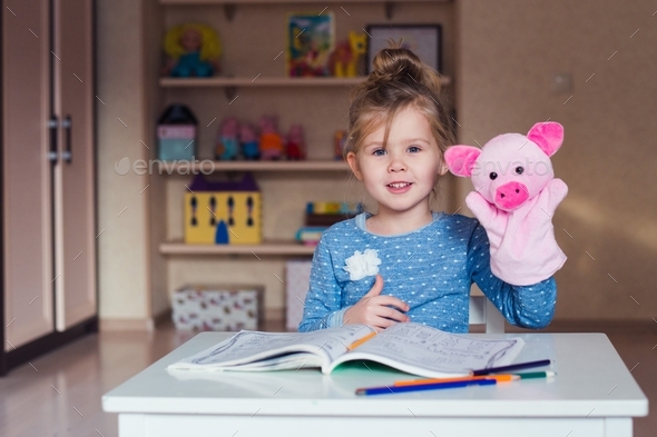 pupil girl doing homework at home with puppet pig Stock Photo by shapoval08
