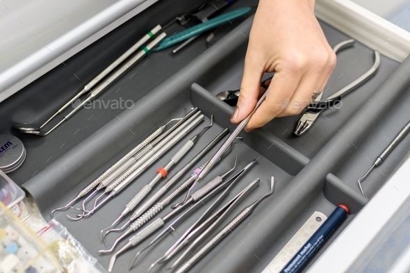 Hand reaching into a drawer to pick up a dental instrument. Stock Photo ...