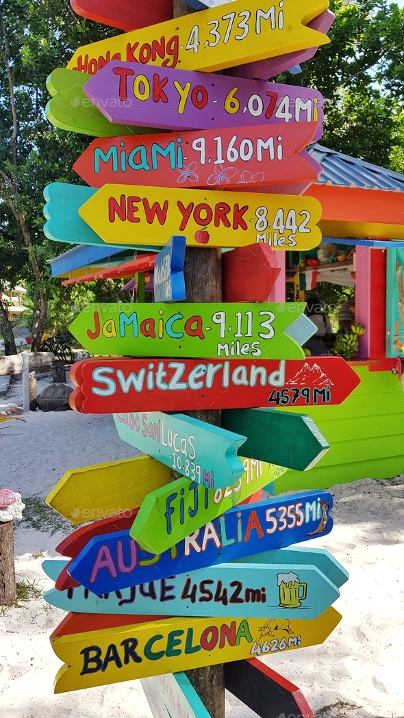 Colorful sign posts in a tropical beach bar. Stock Photo by anelehbakota