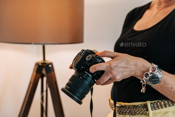 Close-up photo of female photographer, standing in room, checking ...