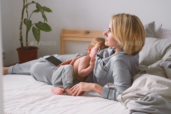 mom breastfeeds little son in the morning in bed Stock Photo by natalyaraeva