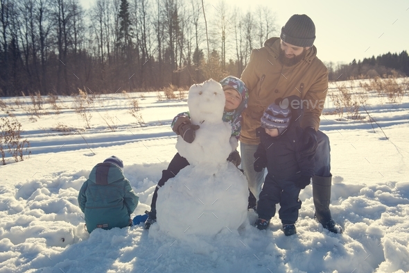 making snowman - father and kids play together outdoors Stock Photo by ...