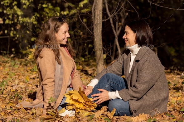 mother and daughter walk in sunny weather in the autumn forest Stock Photo by aliliya