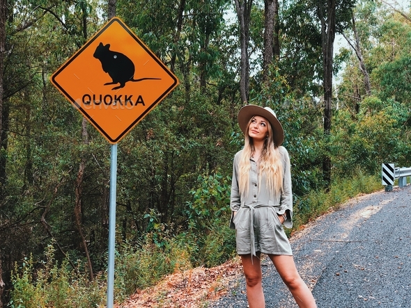 Beautiful blonde traveler girl wearing hat next to quokka sign in ...