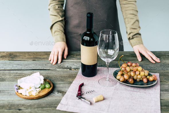 Female sommelier standing near table with wine and food Stock Photo by ...