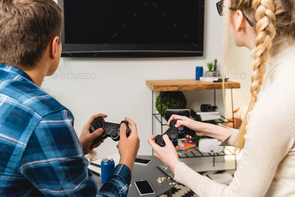 back view of female and male teens playing video game Stock Photo by ...
