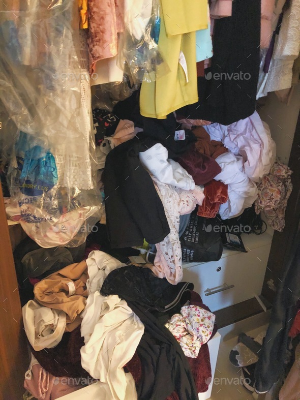 Messy wardrobe with clothes tucked away Stock Photo by phoenixproduction