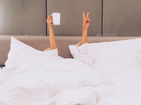 Hands with piece gesture and coffee in another hand poking out from the ...