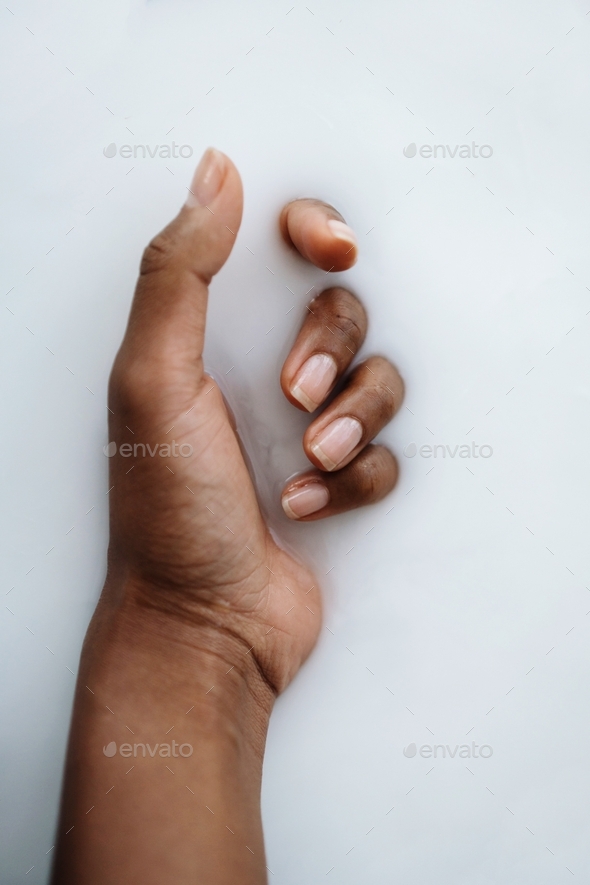 Dark skin hands submerged into milky like water substance Stock Photo ...