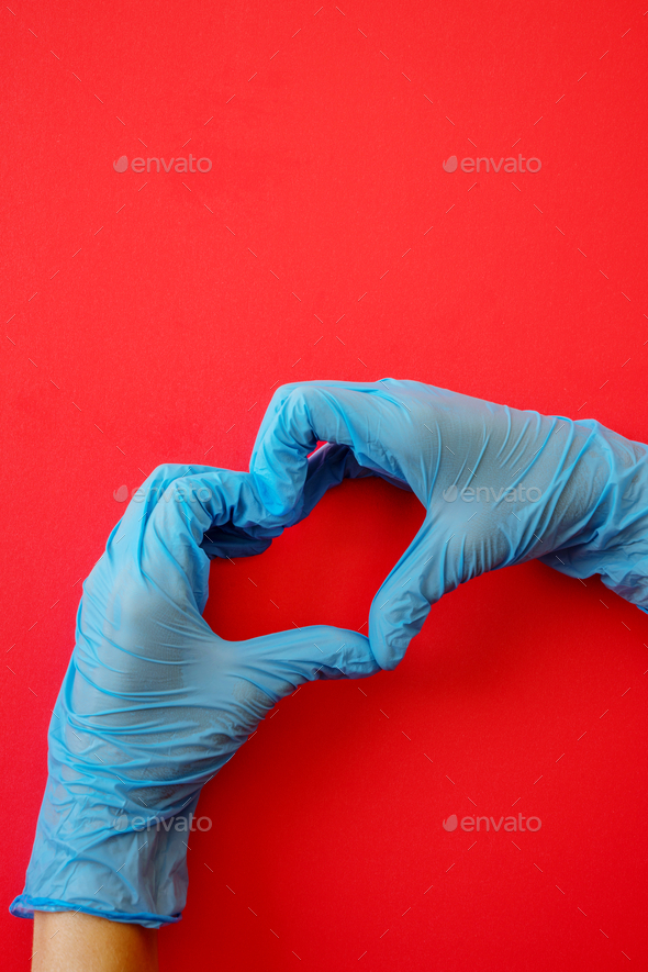 Hand in blue plastic glove making heart shape on a red background Stock ...