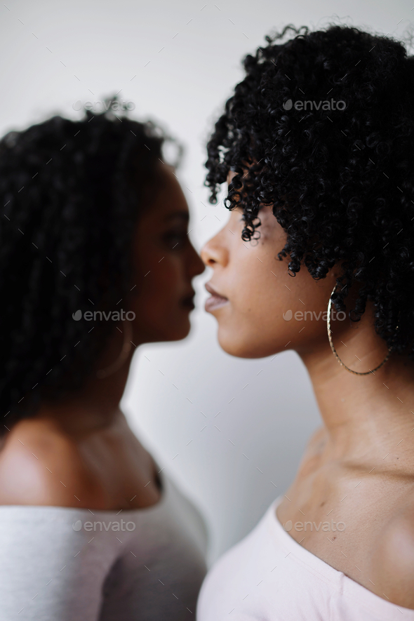 Portrait of two beautiful young women with dark skin opposite each ...