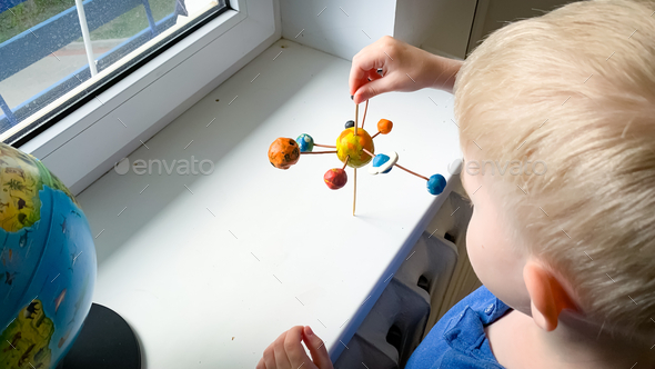 The child holds in his hands a model of the solar system, which he ...