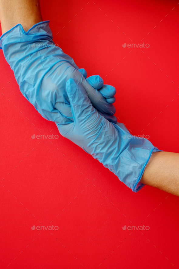 Hand in blue plastic glove making handshake on a red background Stock ...