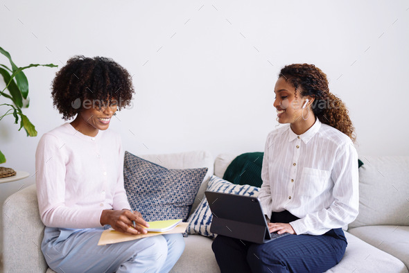 Two black women sitting down on the couch having an interview in a ...