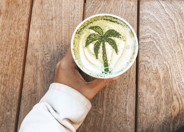 Hand holding Matcha latte with a palm tree art Stock Photo by ...