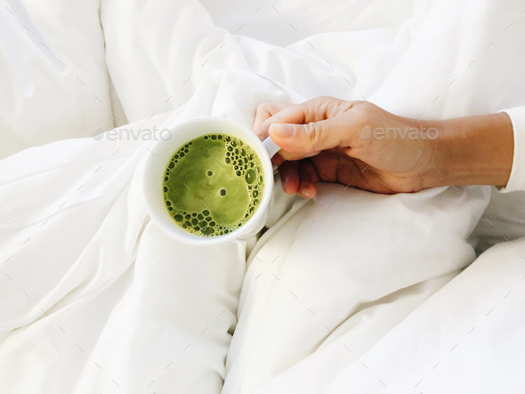 Hand holding matcha latte on bed Stock Photo by phoenixproduction ...