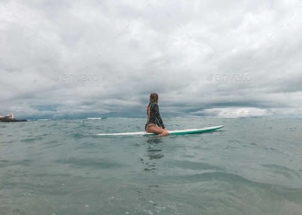 In the ocean surfing sitting on a surfboard Stock Photo by ...