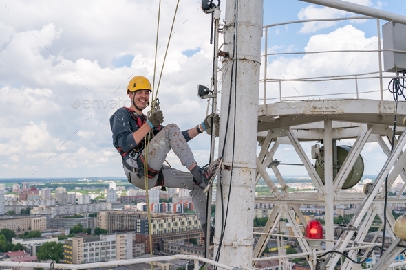 A worker with climbing equipment serves a city TV tower. Work at a high ...