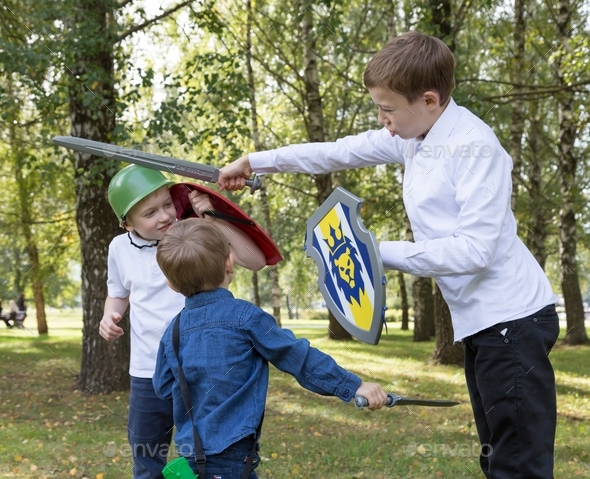 Caucasian boys play war in a public park in summer. Military battle ...