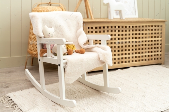 White baby rocking chair with soft toys on the seat in the interior of ...
