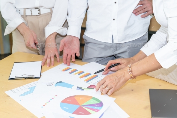 People's hands over the table with charts and graphs closeup. Business ...
