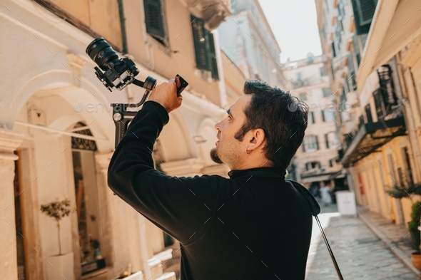 Male cameraman shoots urban architecture and building facades with ...