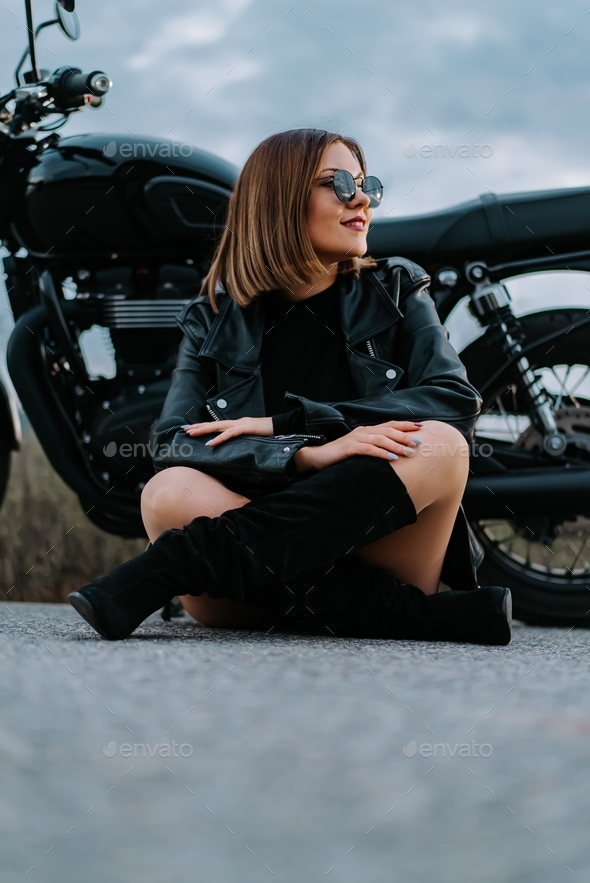 Motorcyclist woman in mini skirt sitting on the asphalt near her retro ...