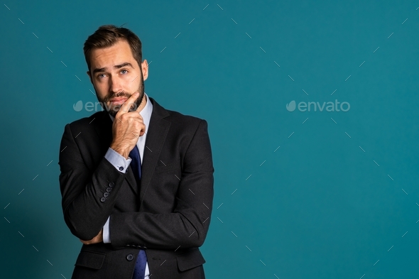 Serious thinking businessman looking around on blue background Stock ...