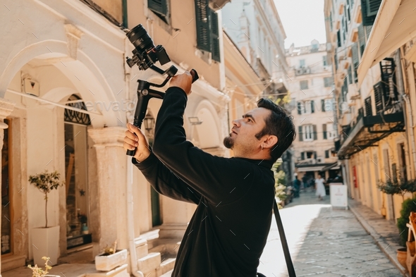Male cameraman shoots urban architecture and building facades with ...
