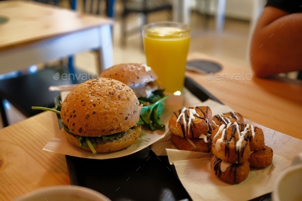 Healthy breakfast in cafe - vegan burger, orange juice and sweet cakes ...