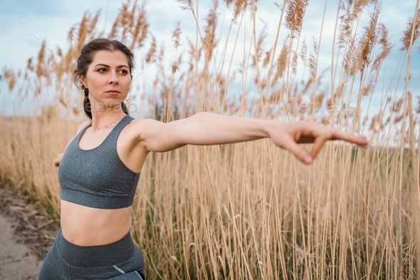European woman doing yoga exercise on reed natural background ...