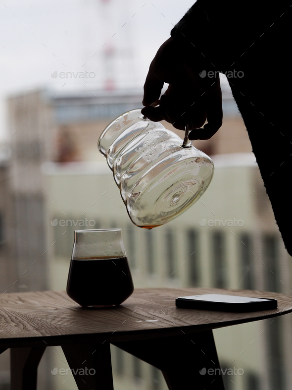 Woman hand pouring hot coffee into glass mug from pour-over carafe ...
