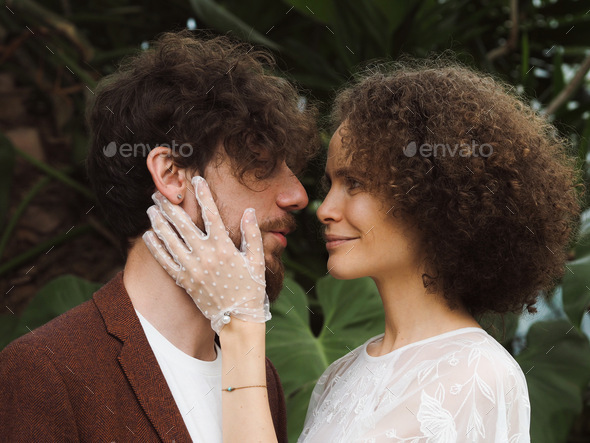 Portrait of a young stylish couple with curly hair on their wedding day ...