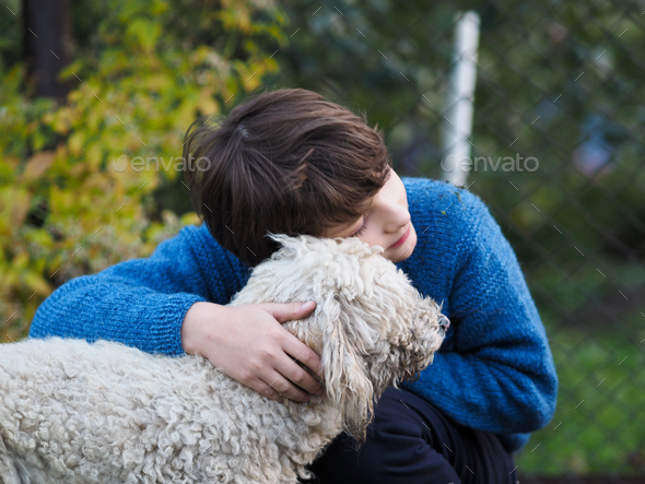 Cute little boy hugging white poodle with love on garden. Love and ...