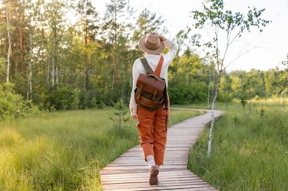 Woman naturalist walking on path through peat bog swamp on ecological ...