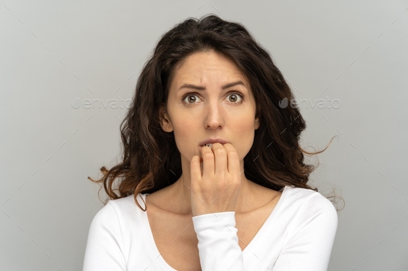 Shy awkward young woman biting nails feeling embarrassed, confused and ...
