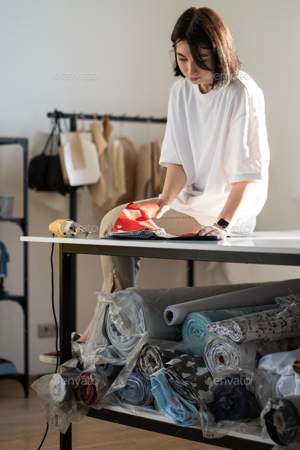 Young designer tailor woman choose swatches of fabric in studio. Girl ...