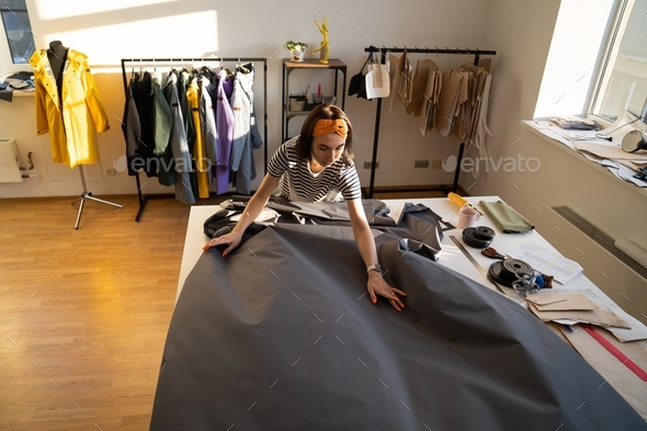 Sewer unroll fabric on atelier table. Fashion designer tailor in ...