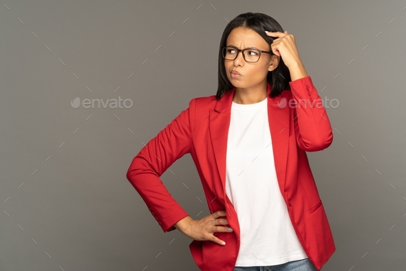 Doubtful mixed race woman touching her head, frowning pondering looking ...