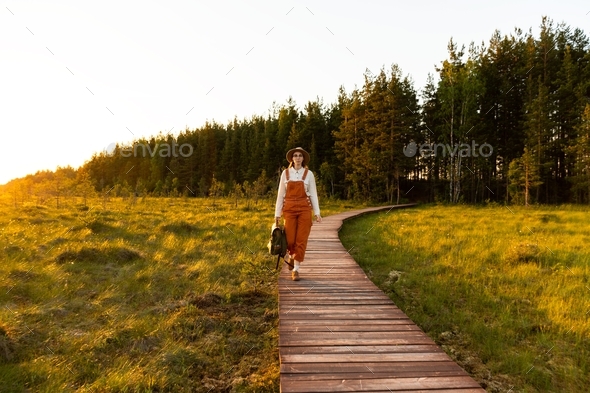 Woman naturalist walking on path through peat bog swamp on ecological ...