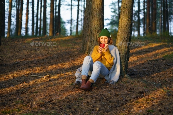 Recreation in nature: happy woman sit under tree in autumn forest ...