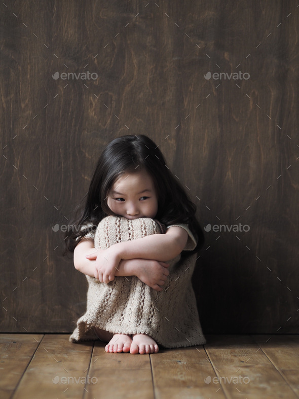Beautiful little asian girl with dark long hair sits on the wooden ...
