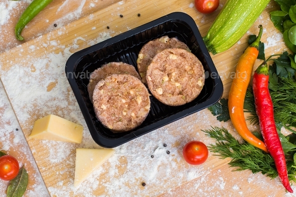 Fresh frozen meat cutlets with cheese and herbs in a plastic box. Semi ...