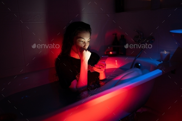 Angry woman sit in clothes in cold bath read messages from ex-boyfriend ...