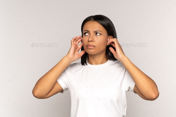 Irritated african woman plugging ears stressed with noise from neighbor ...