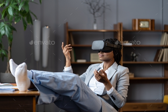 Relaxed afro woman in VR headset meditating in virtual reality at ...