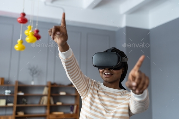 Pretty young black woman in VR headset looking and trying to touch ...